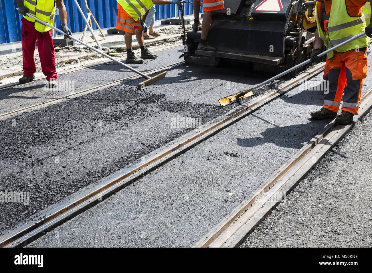 Workers construct asphalt road and railroad lines Stock Photo - Alamy