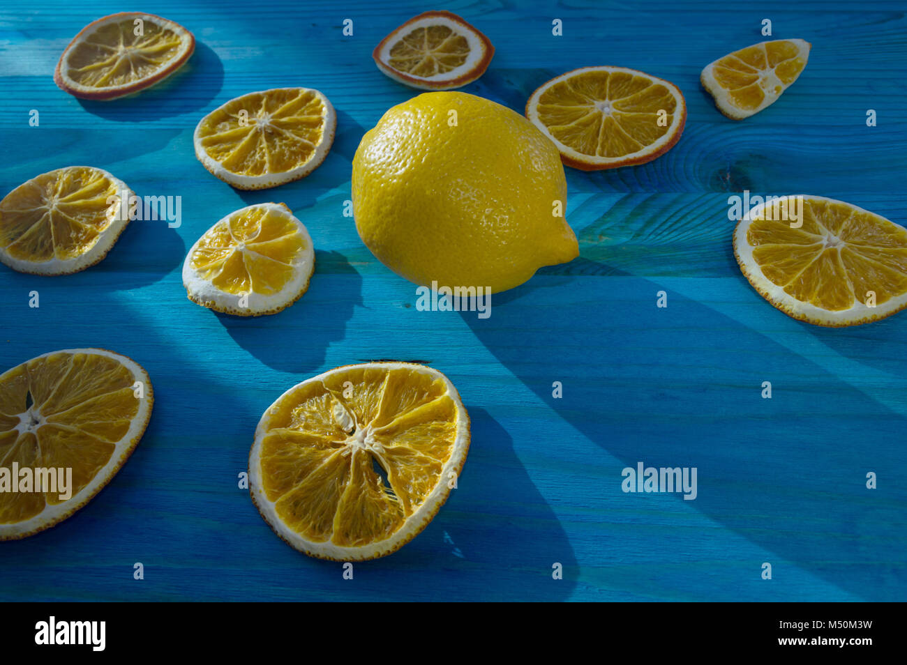 lemon and orange slices on blue wooden background under sunlight Stock ...