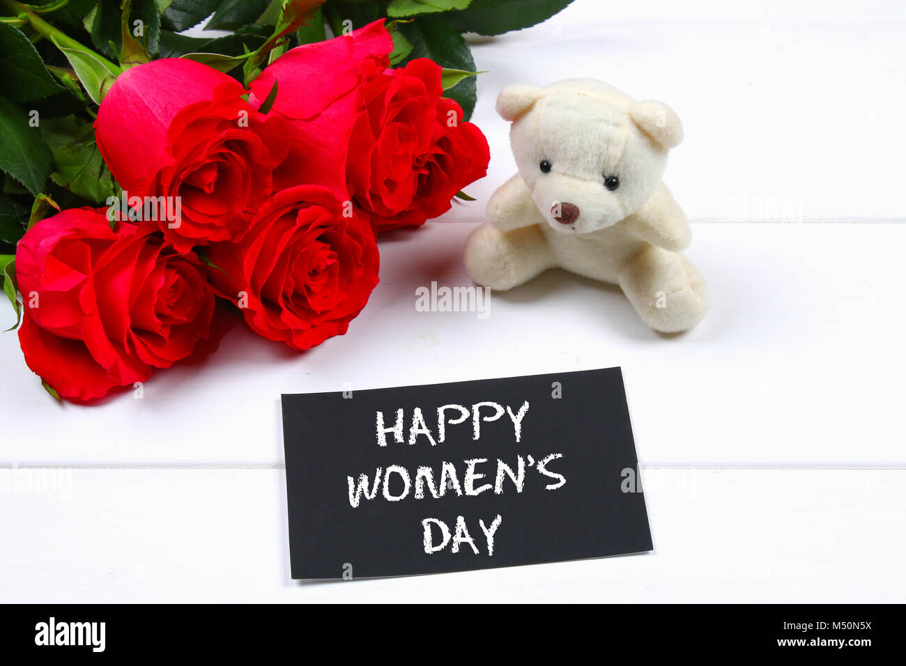 Happy woman's day. March 8. Roses, teddy bear and chalkboard on a white ...