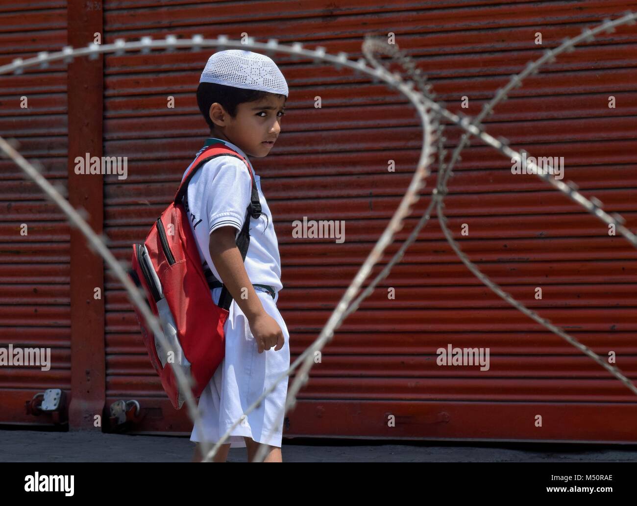 Srinagar, Kashmir. 19th Feb, 2018. A Kashmiri school boy stands raveled ...