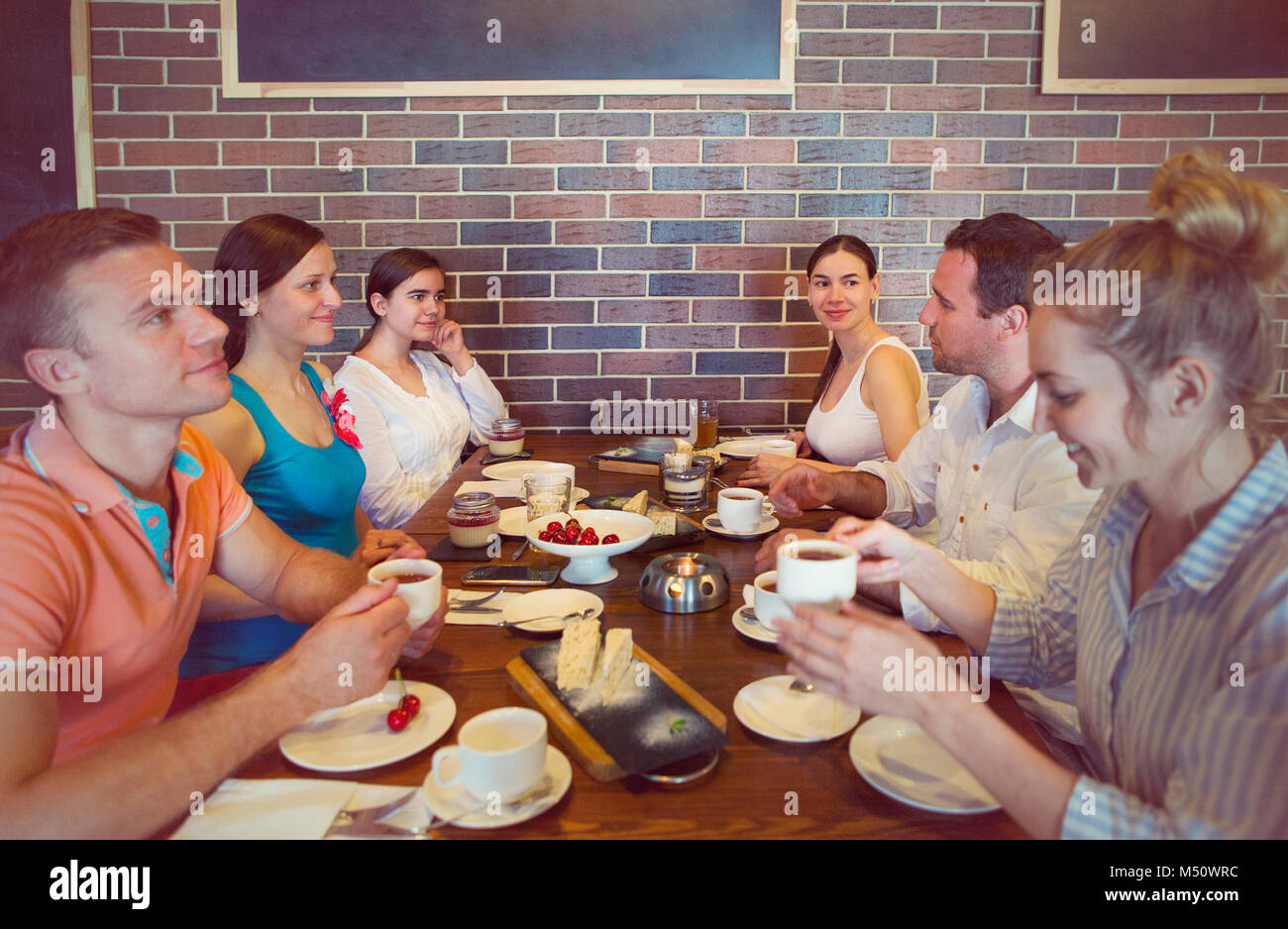 Six cheerful friends chatting while lunch in restaurant. Friendship and ...