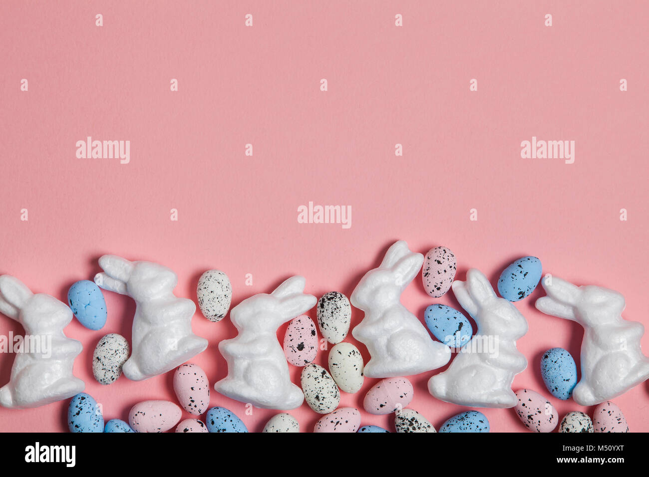 Pastel pink easter holiday background with eggs and easter bunnies ...