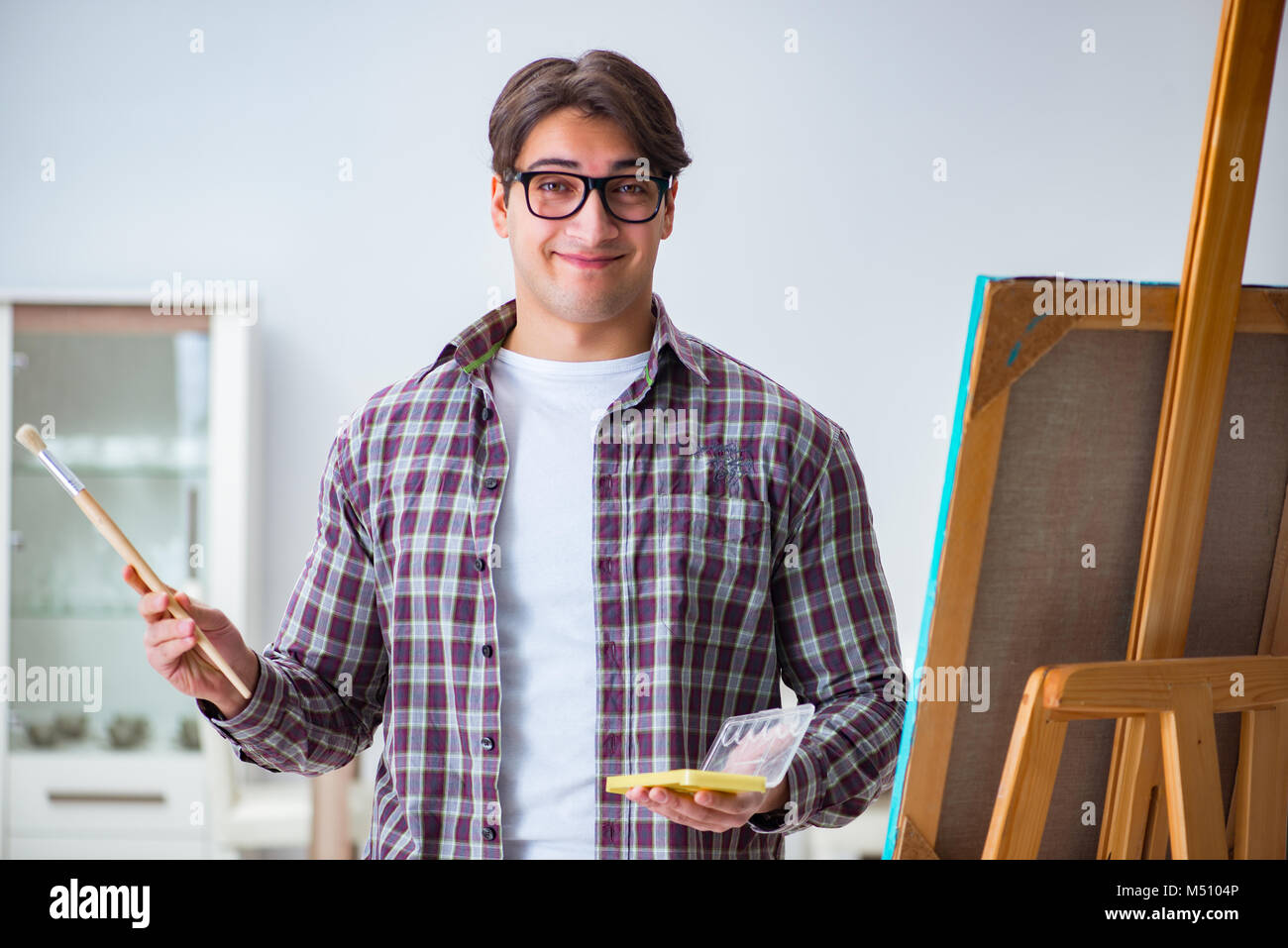 Young male artist drawing pictures in bright studio Stock Photo - Alamy