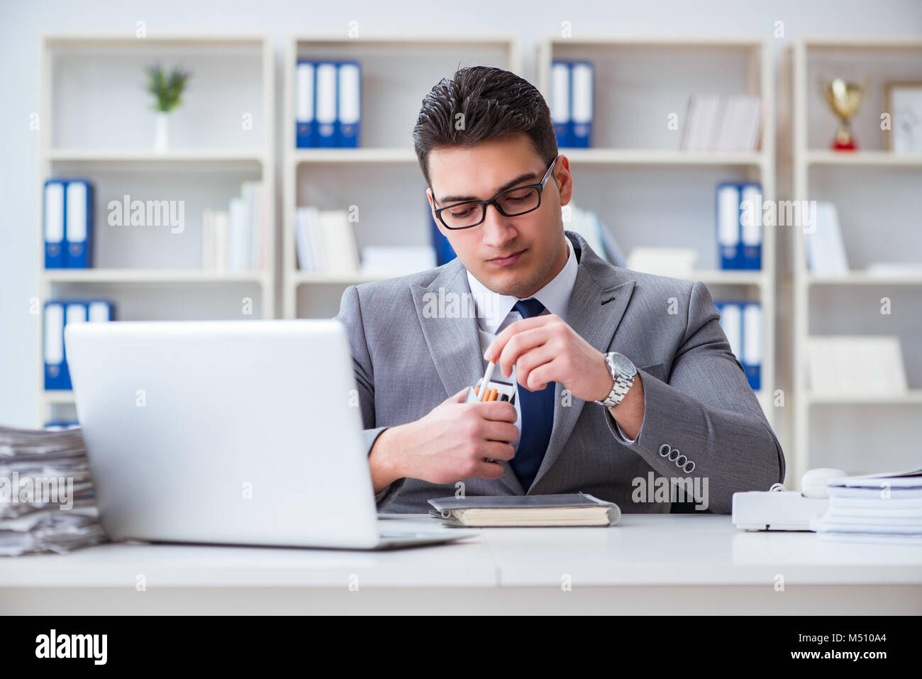 Businessman smoking in office at work Stock Photo - Alamy