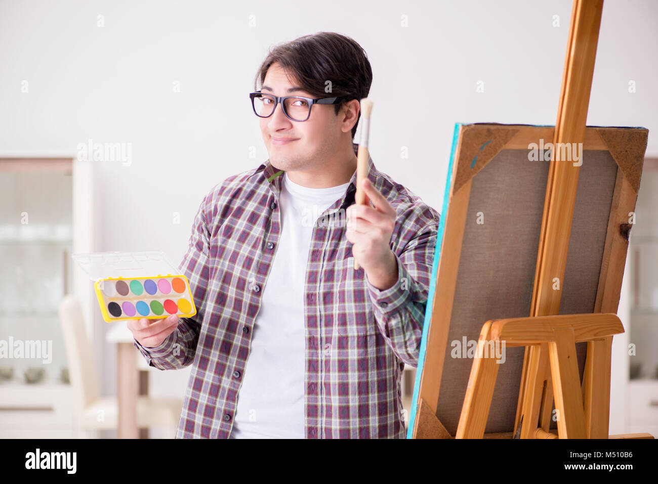 Young male artist drawing pictures in bright studio Stock Photo - Alamy