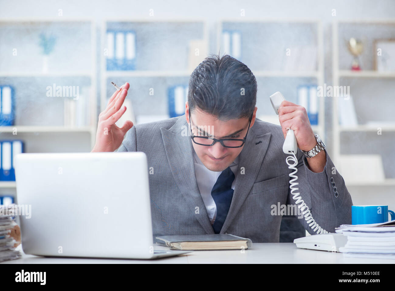 Businessman smoking in office at work Stock Photo - Alamy