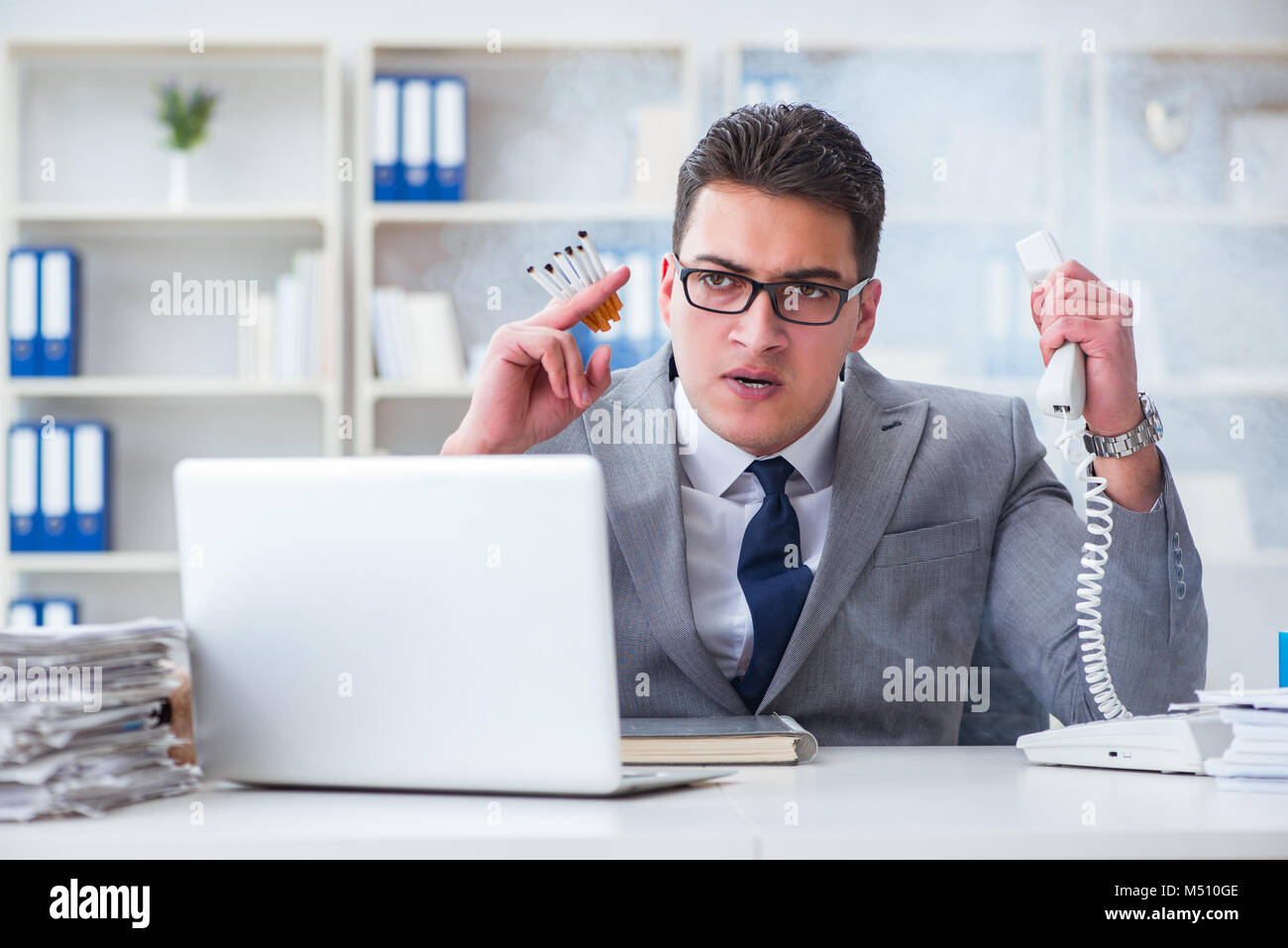 Businessman smoking in office at work Stock Photo - Alamy