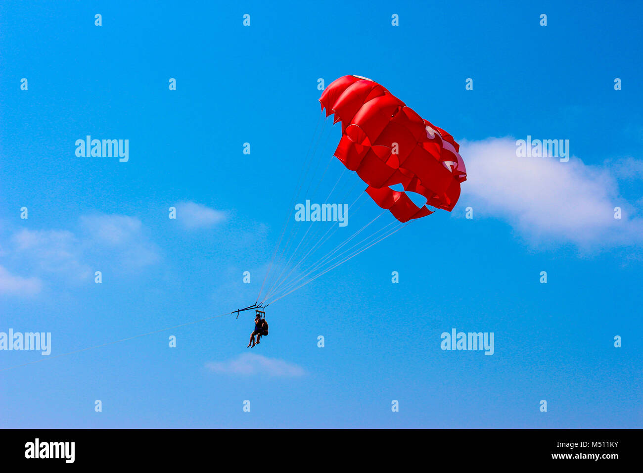 Tourist parasailing in front of blue sky, red parasail in Side, Turkey ...