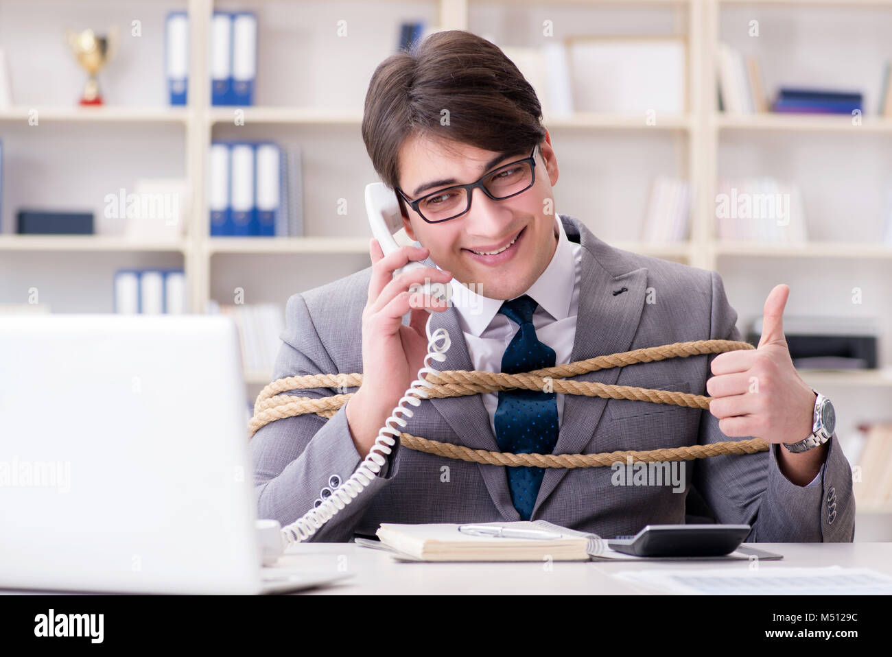 Businessman tied up with rope in office Stock Photo - Alamy