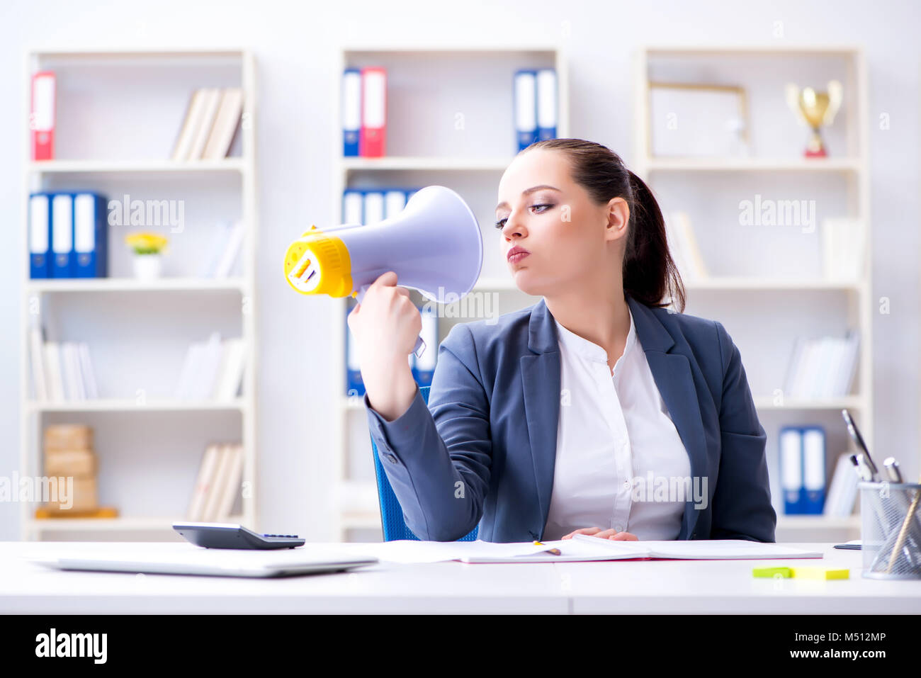 Angry businesswoman yelling with loudspeaker in office Stock Photo - Alamy