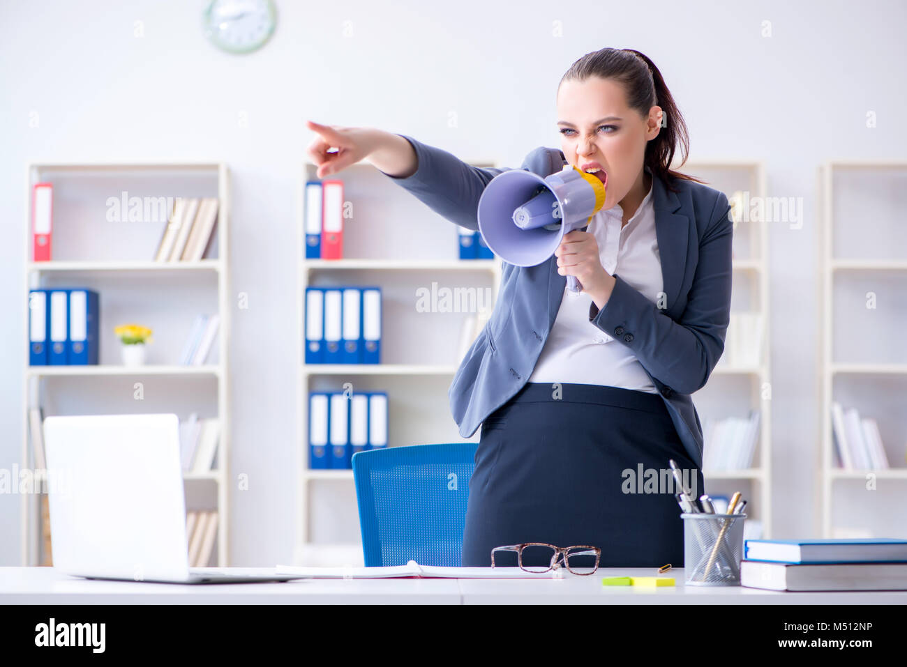 Angry businesswoman yelling with loudspeaker in office Stock Photo - Alamy