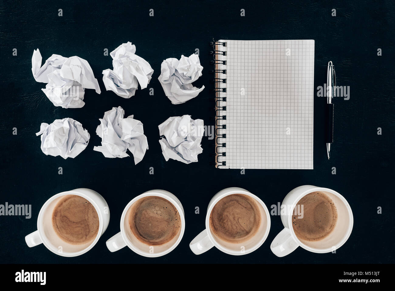 top view of blank notebook with crumpled papers and cups of coffee in ...