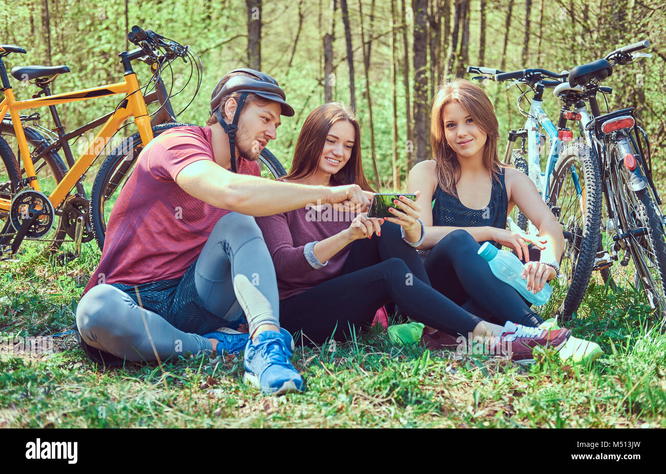 Group of young friends hiking through the forest with bikes on a Stock ...
