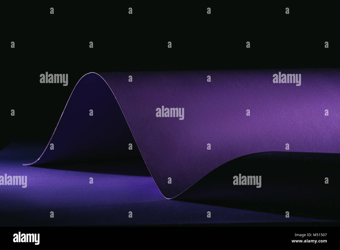warping purple paper on purple surface on black Stock Photo - Alamy
