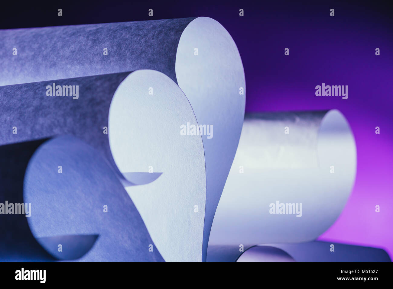 close up view of white paper curves on each other on dark purple Stock ...