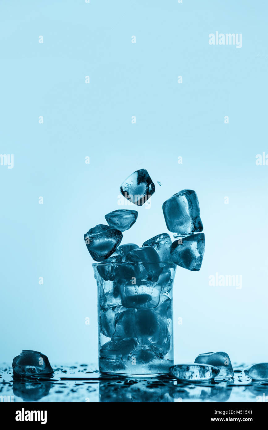 melting ice cubes falling into glass, on white with drops Stock Photo ...