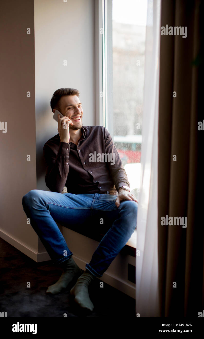 Handsome young man using mobile phone in the room Stock Photo - Alamy