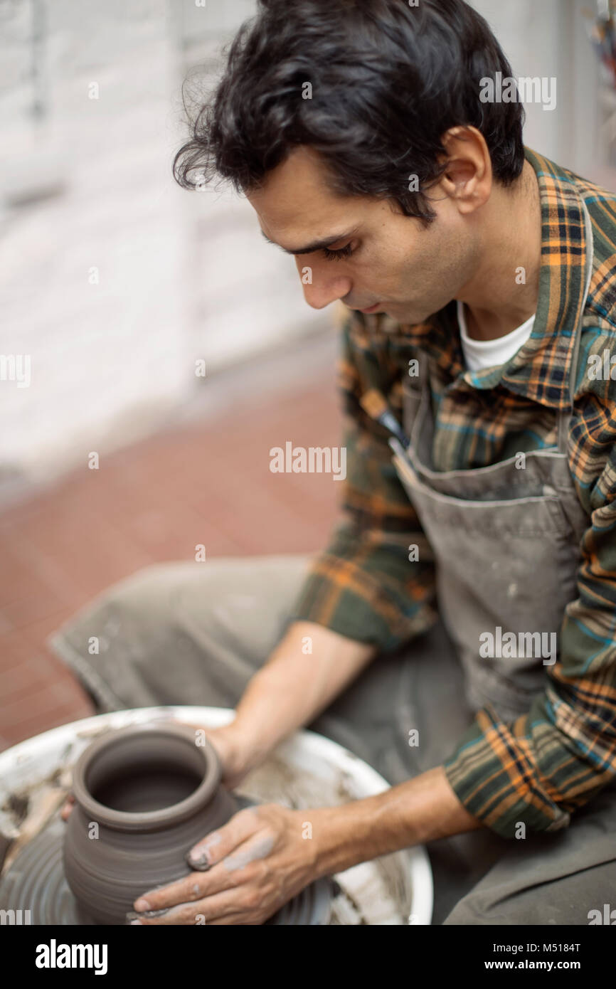 View at an artist makes clay pottery on a spin wheel in workshop Stock ...
