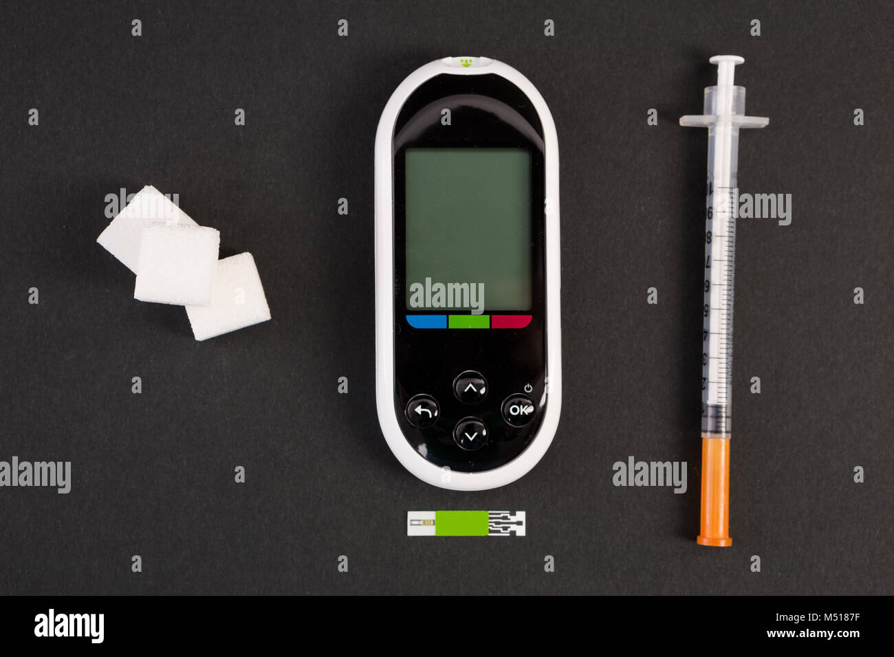 Insulin syringe glucometer and white sugar cubes on black background as ...