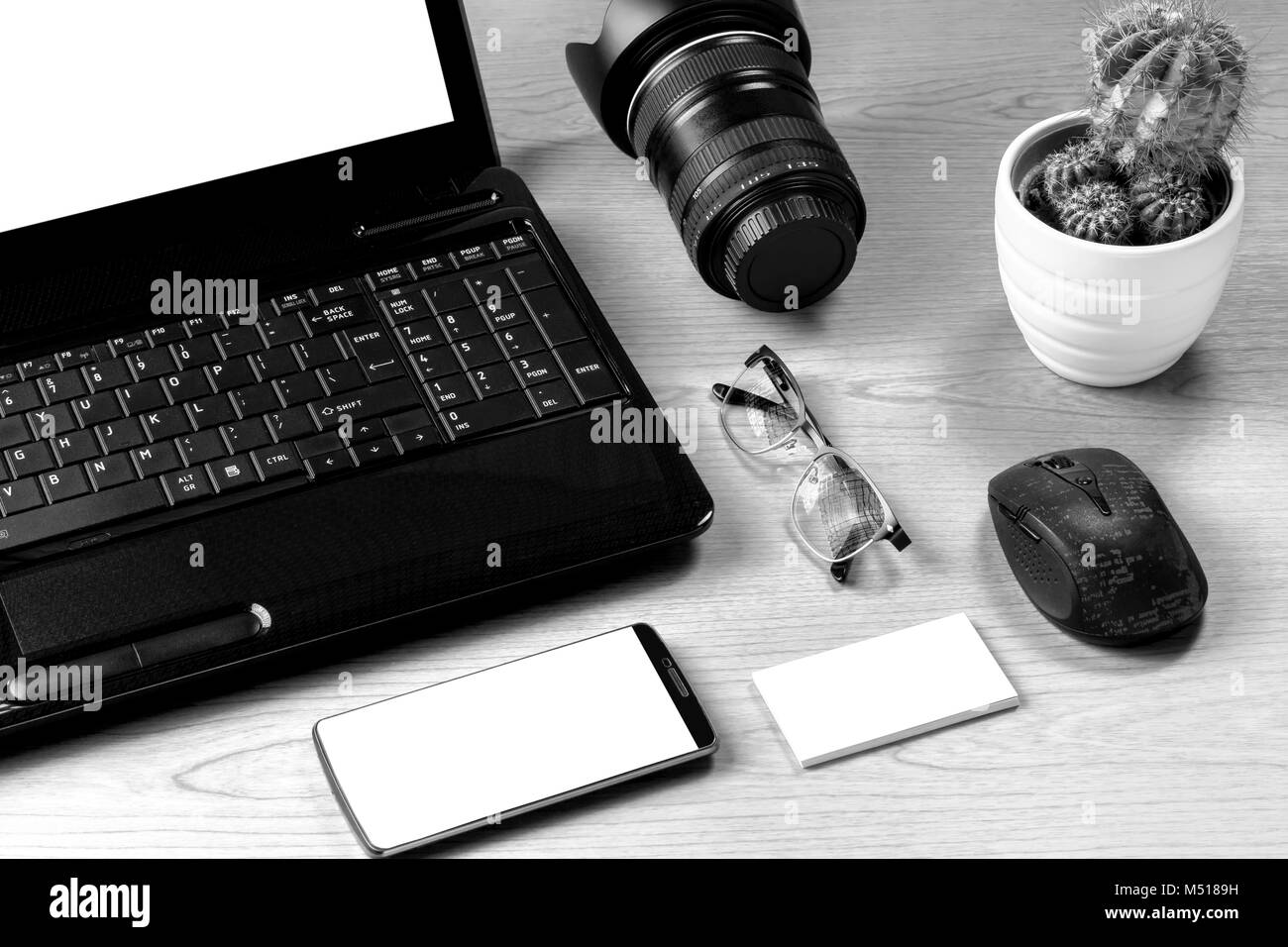 Office table with laptop computer, camera lens, smartphone, eyeglass ...