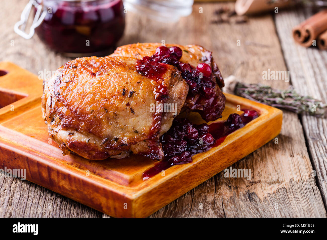Roast chicken legs on cutting board served with cranberry sauce on ...