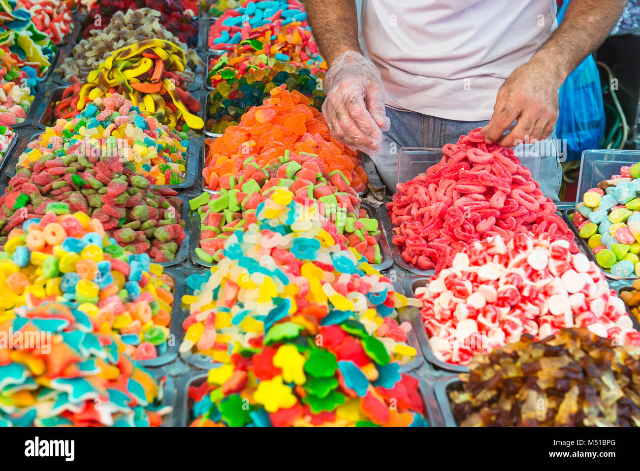 Seller unfolds sweets on counter with assorted colorful different shape ...