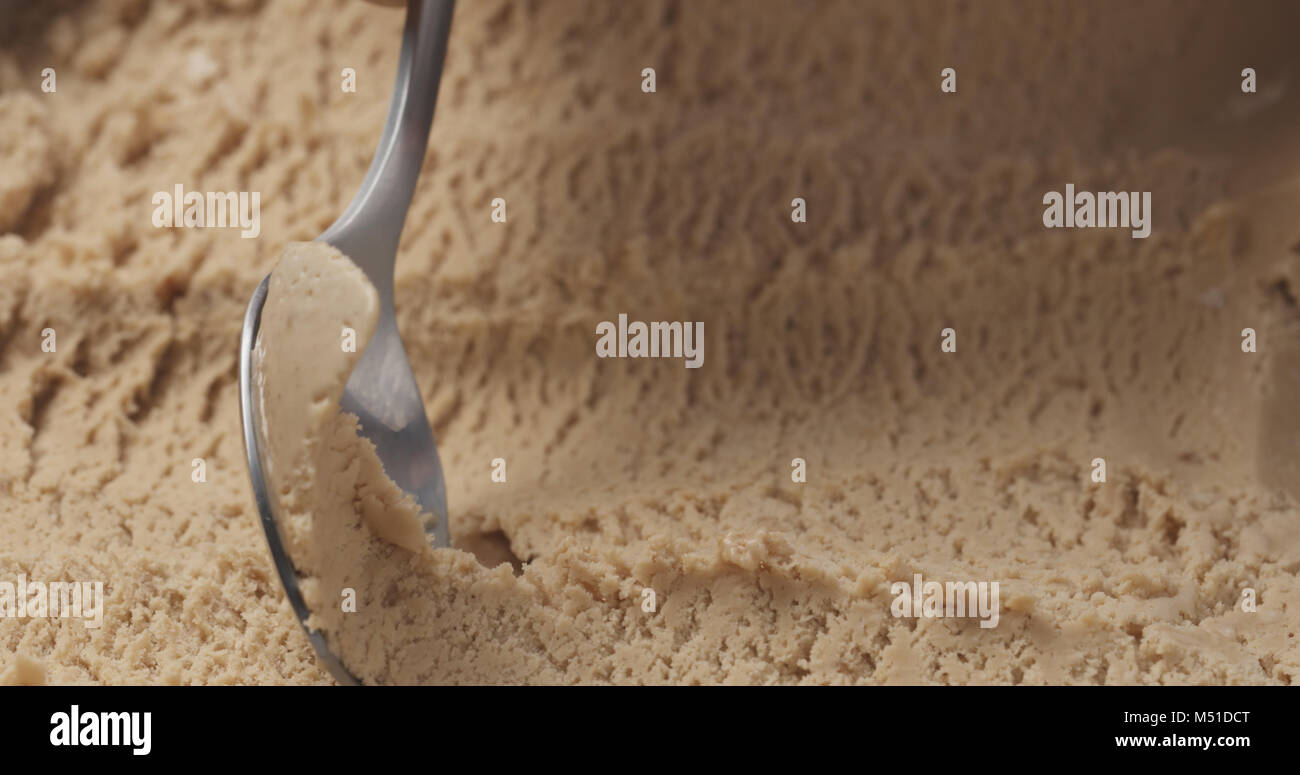 closeup hazelnut praline ice cream scooping with spoon, wide photo ...