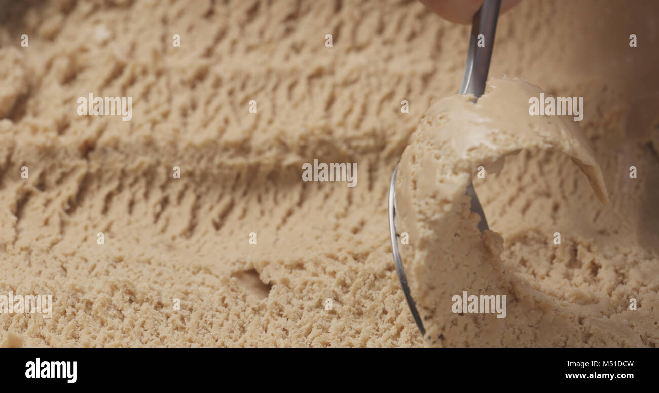 closeup hazelnut praline ice cream scooping with spoon, wide photo ...