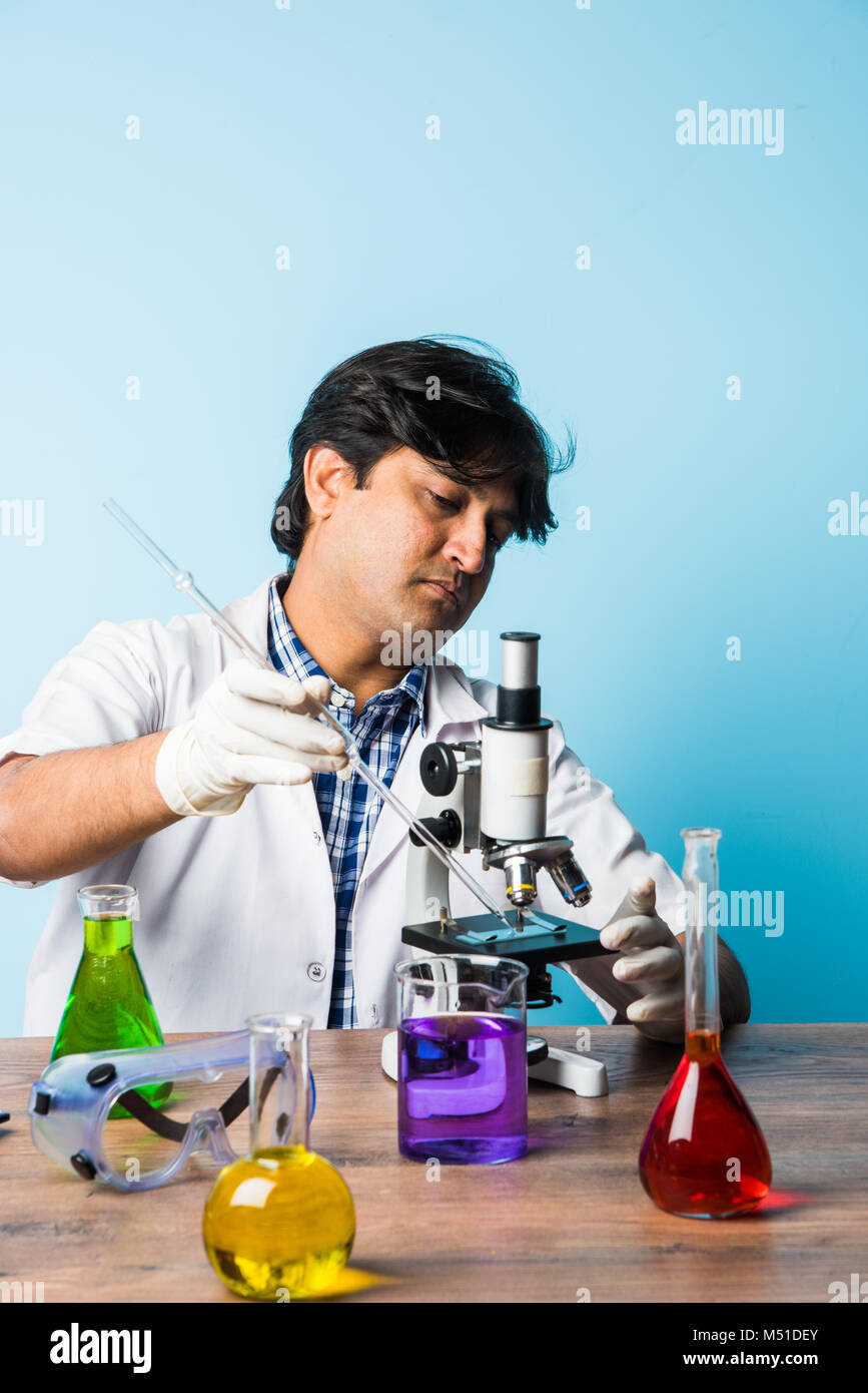 Asian/Indian male scientist or doctor or science student experimenting ...