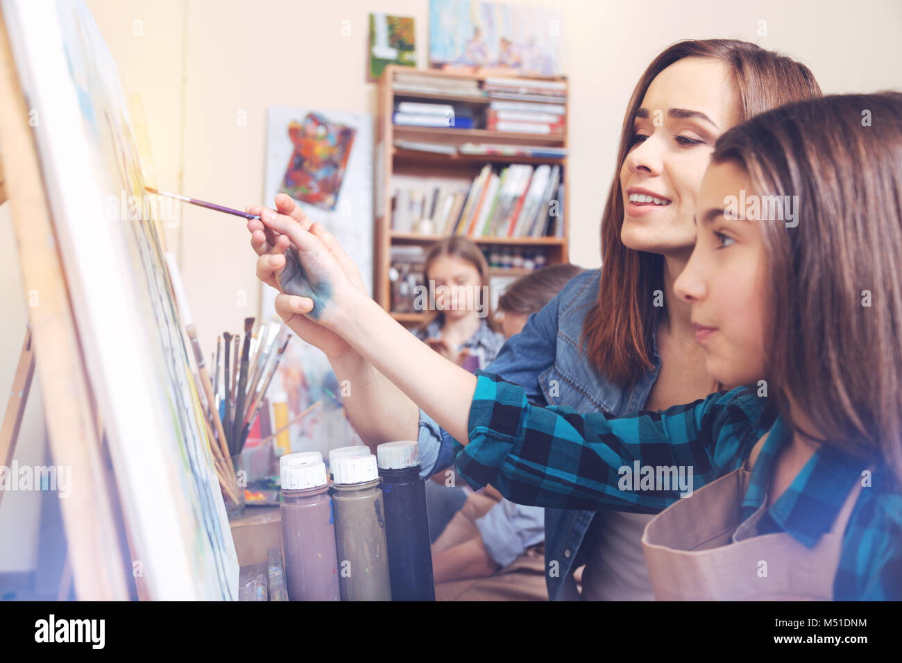 Young woman helping student with painting Stock Photo - Alamy