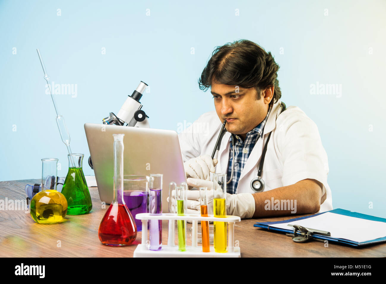 Asian/Indian male scientist or doctor or science student experimenting ...