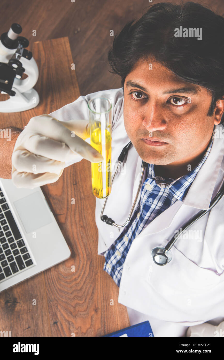 Asian/Indian male scientist or doctor or science student experimenting ...