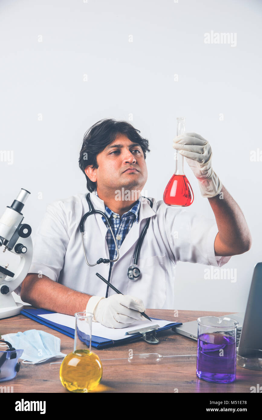 Asian/Indian male scientist or doctor or science student experimenting ...