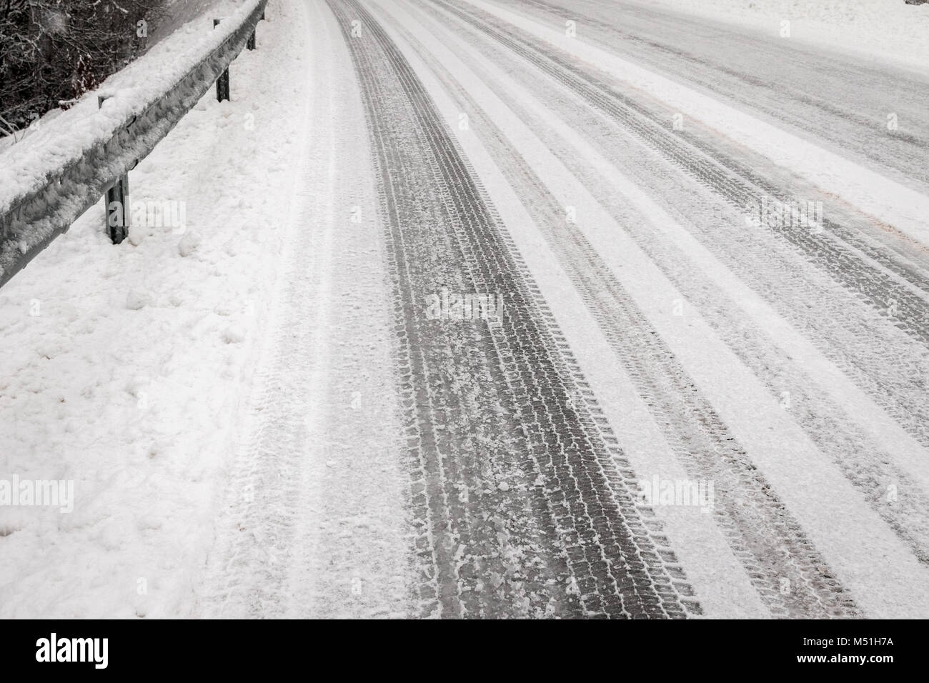 background texture of crash barriers and asphalt road covered with snow ...