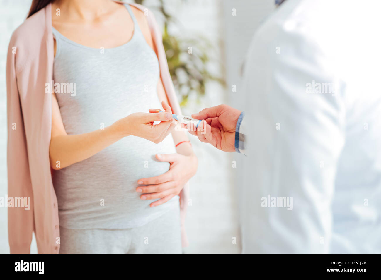Scaled up look on expectant mother giving doctor thermometer Stock ...