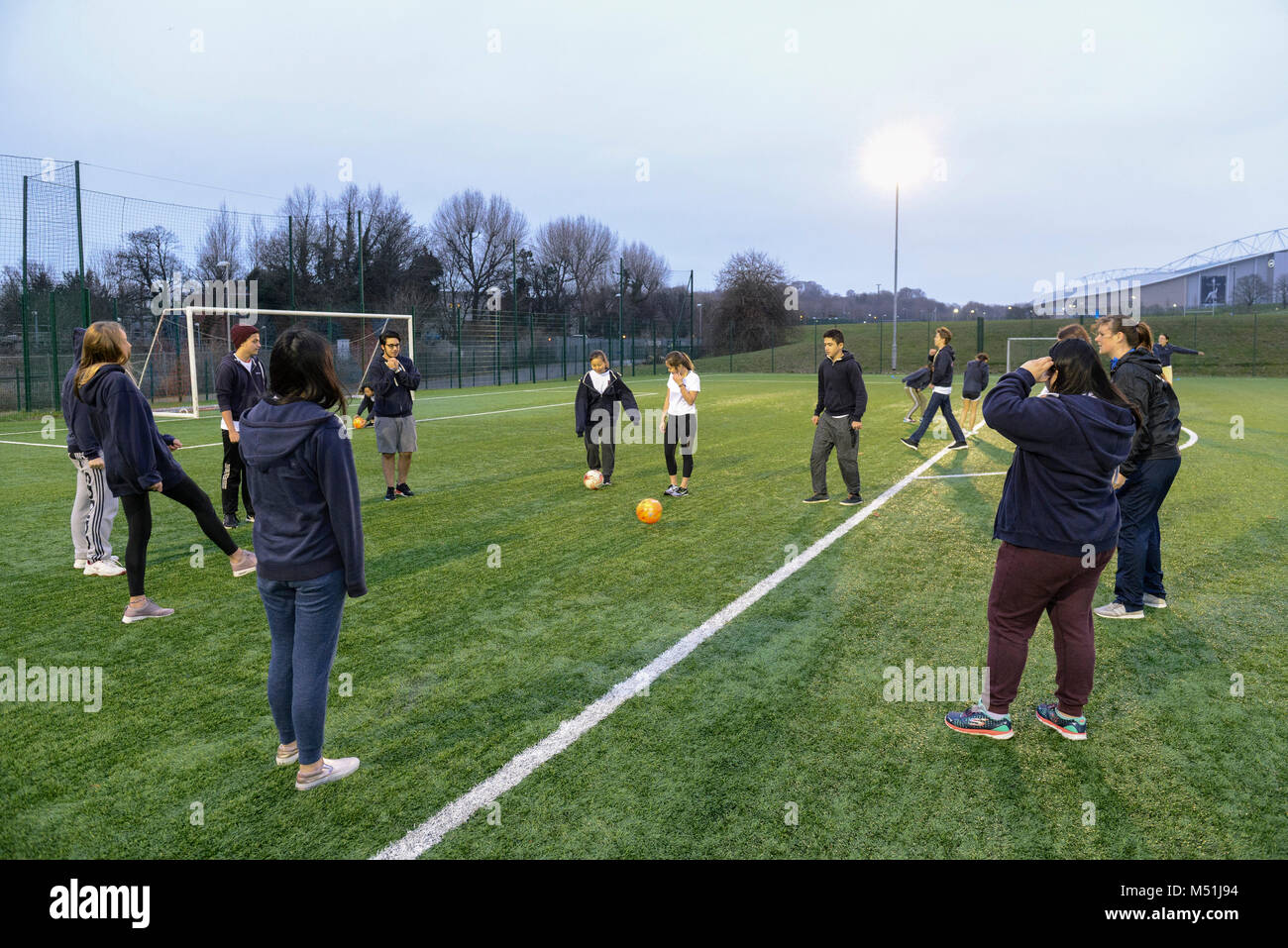 school students having a football lesson to improve their skills at ...
