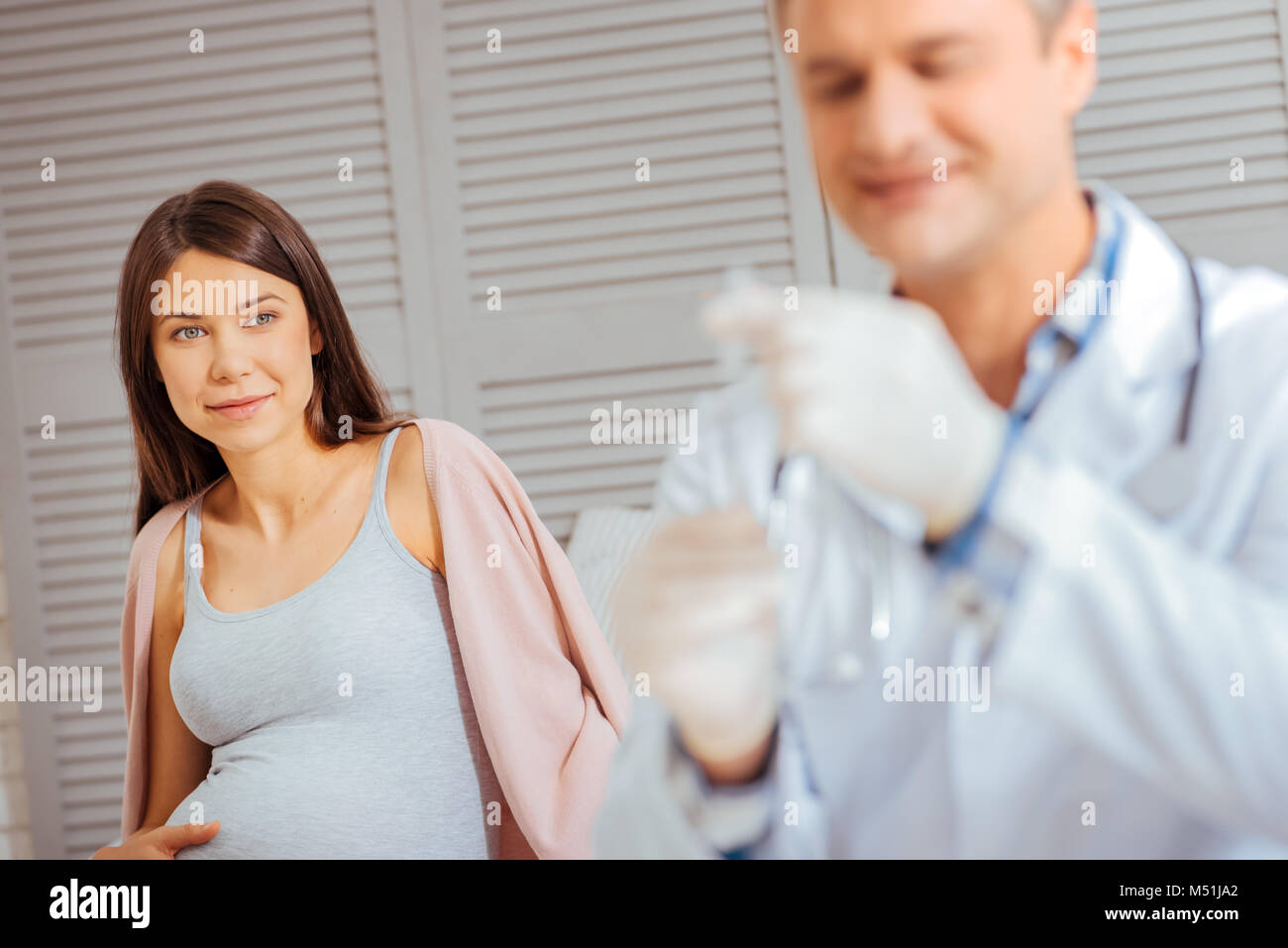 Pregnant woman looking at doctor preparing syringe Stock Photo - Alamy
