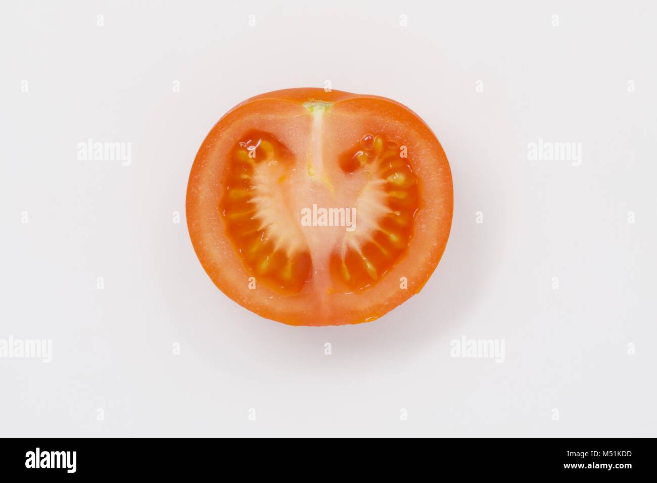 A tomato sliced in half on a white plain background Stock Photo - Alamy