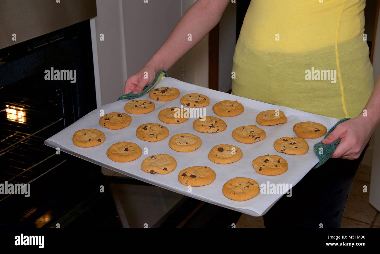 Close up on young female hands pulling tray of soft and chewy chocolate ...