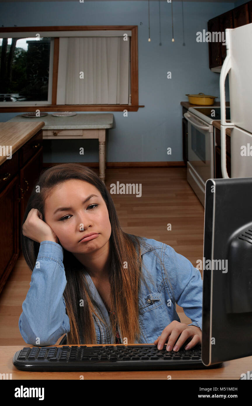 Frustrated bored teenage girl using a desktop computer to do homework ...