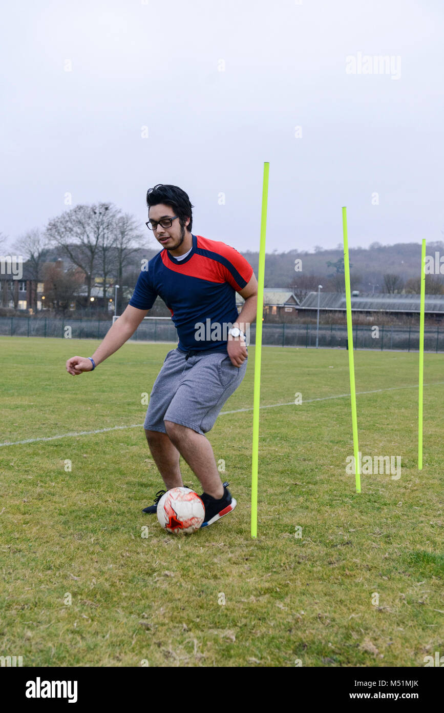 school students having a football lesson to improve their skills at ...