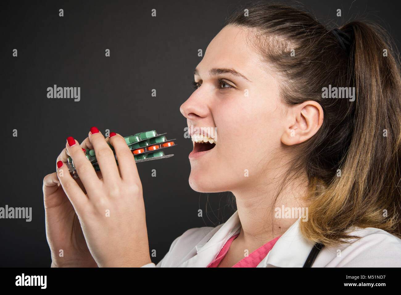 Close-up of attractive female doctor eating bunch of blisters with ...