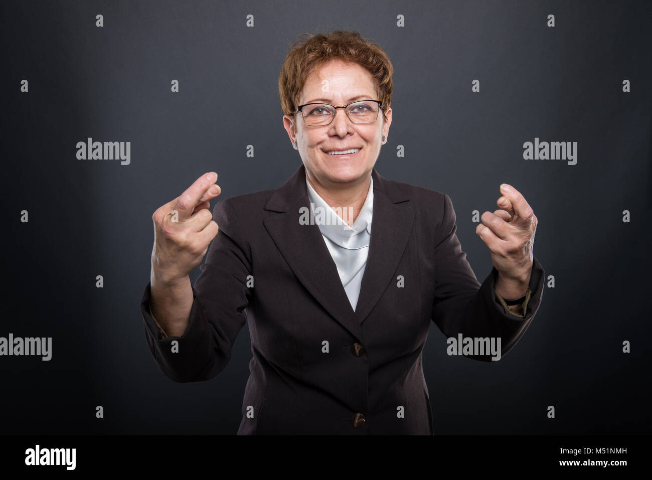 Business senior lady showing double fingers crossed on black background ...