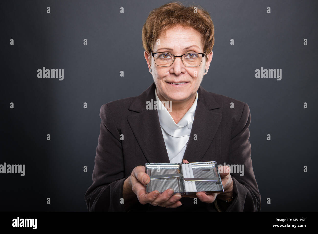 Business senior lady holding cigarette box and smiling on black ...