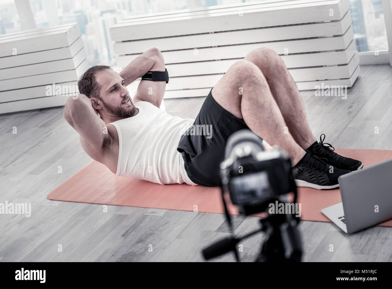 Bearded male blogger making crunches Stock Photo - Alamy