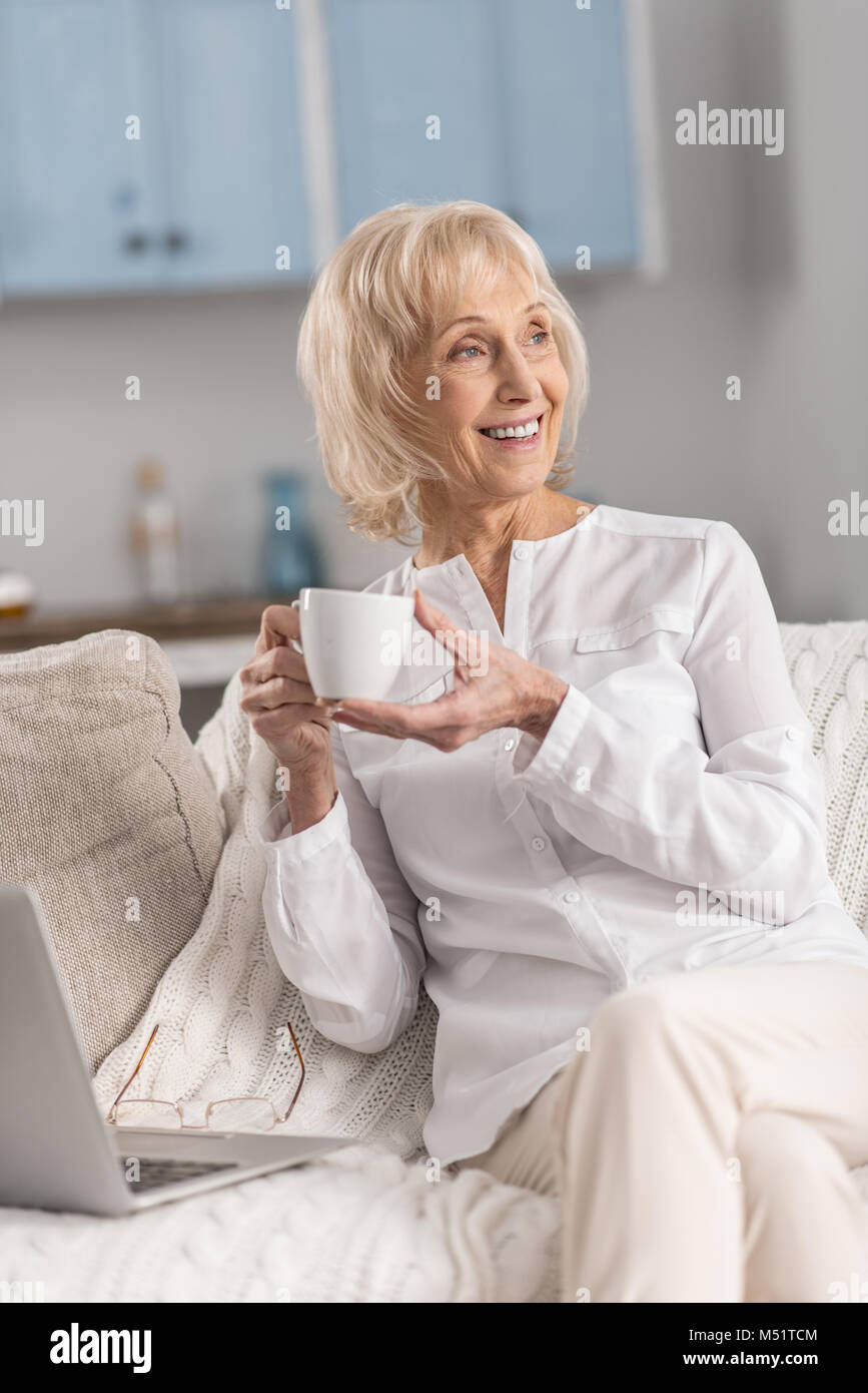 Dreamful mature woman distracting from laptop Stock Photo - Alamy