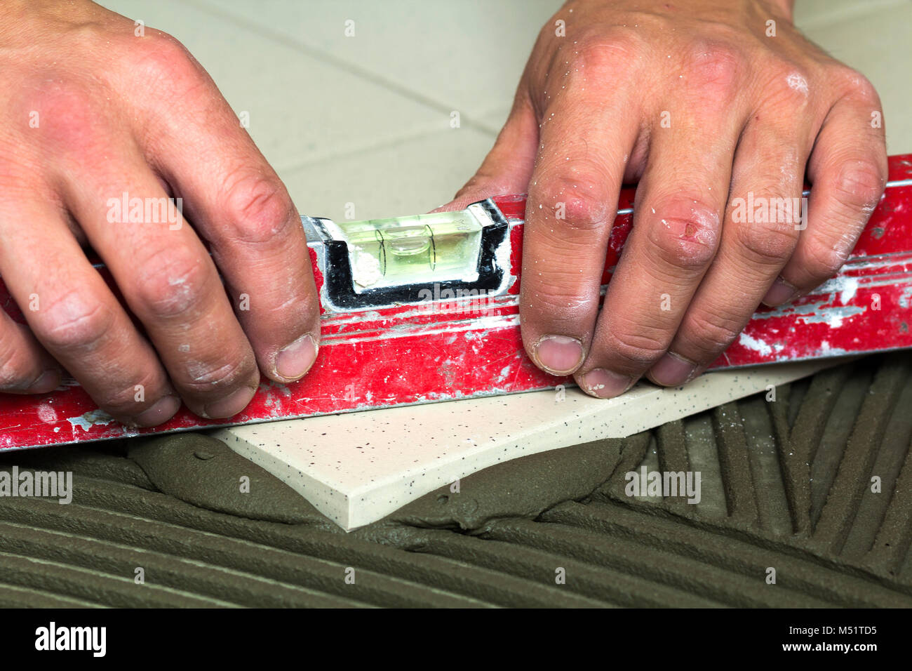 Ceramic tiles and tools for tiler. Worker hand installing floor tiles ...