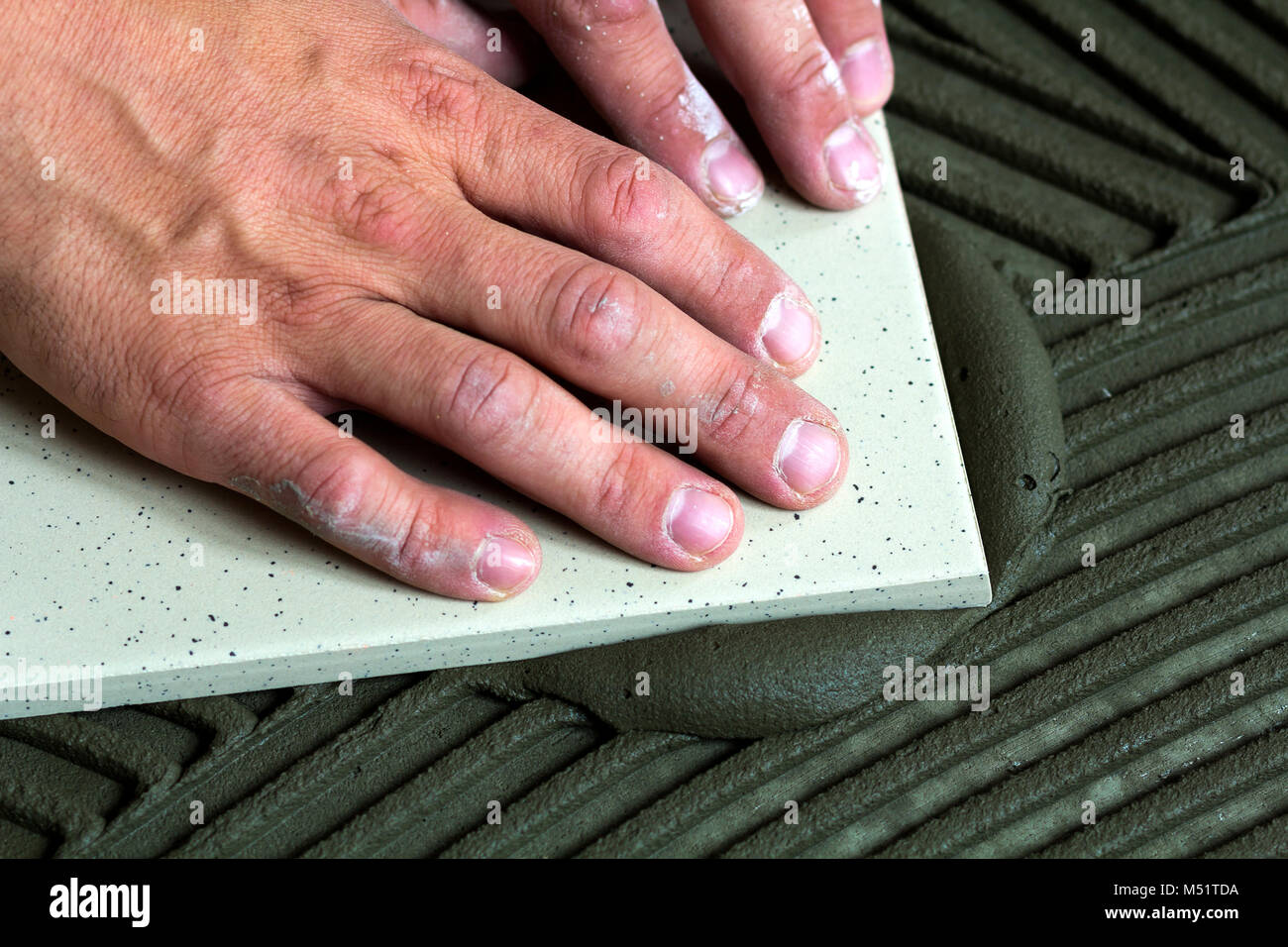 Ceramic tiles and tools for tiler. Worker hand installing floor tiles ...