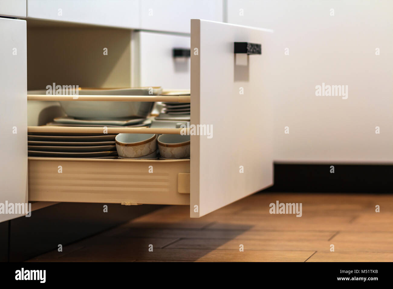 Open kitchen drawers with plates and cups dishes Stock Photo - Alamy
