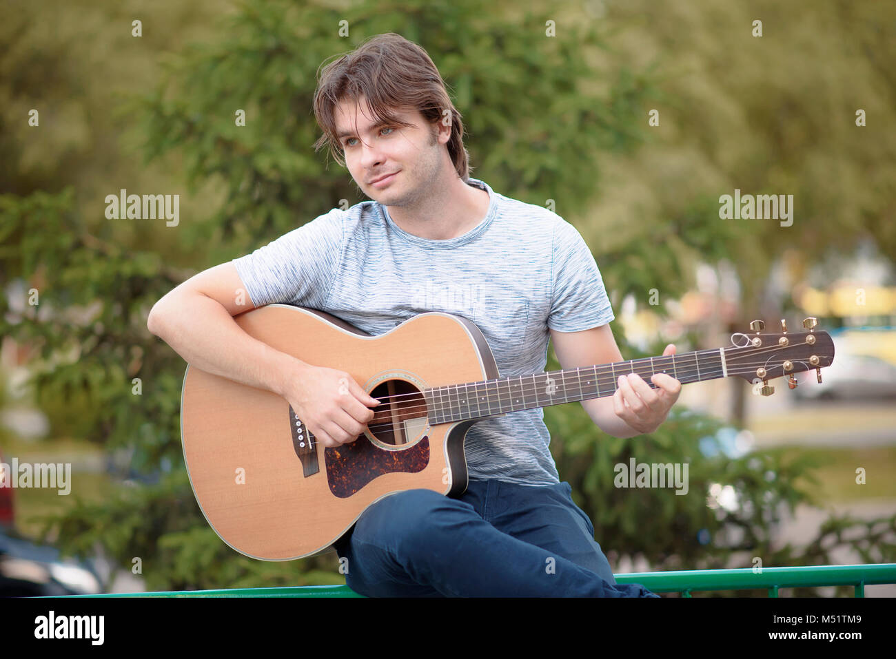 Young man playing guitar outdoors Stock Photo - Alamy